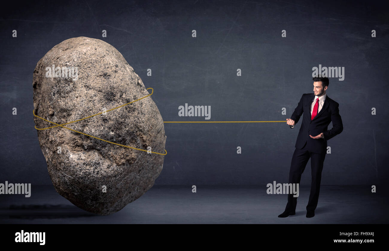 Businessman pulling huge rock with a rope Stock Photo - Alamy