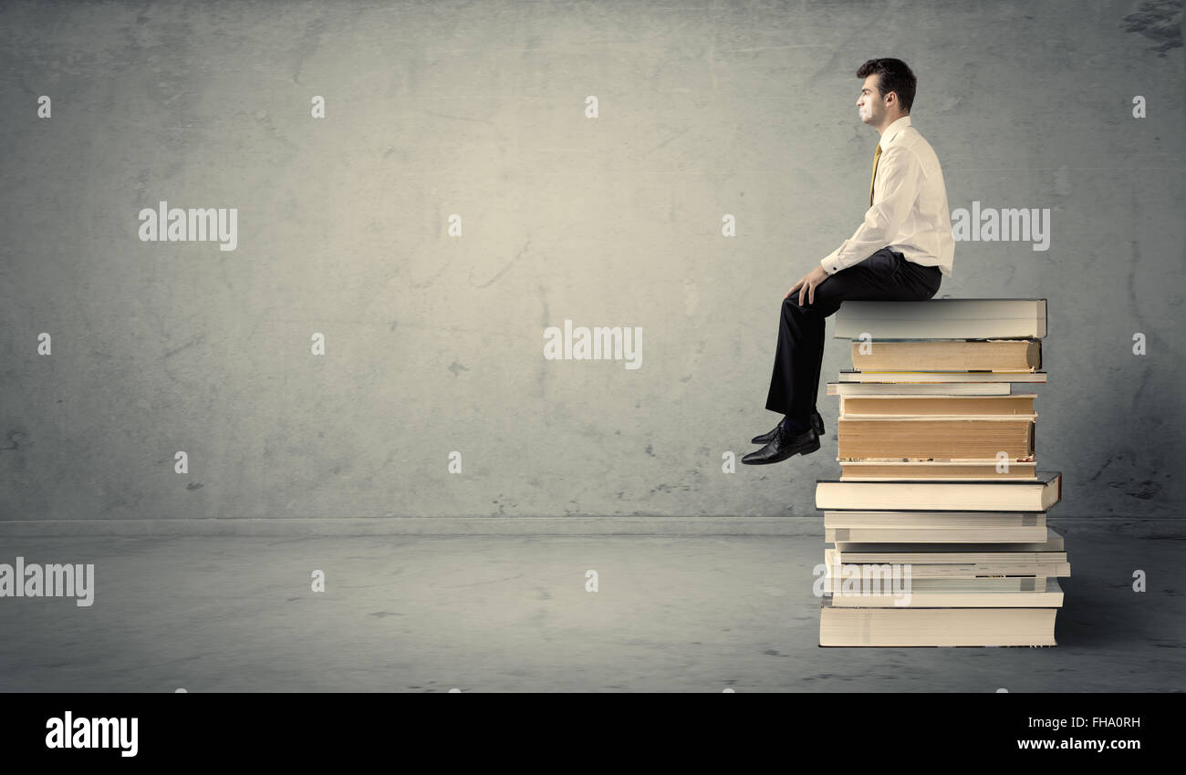 Student sitting on stack of books Stock Photo - Alamy