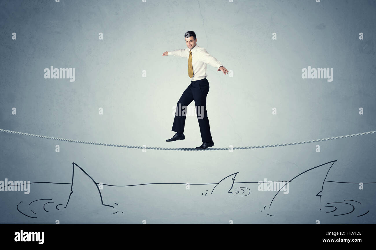 Businessman walking on rope above sharks Stock Photo - Alamy