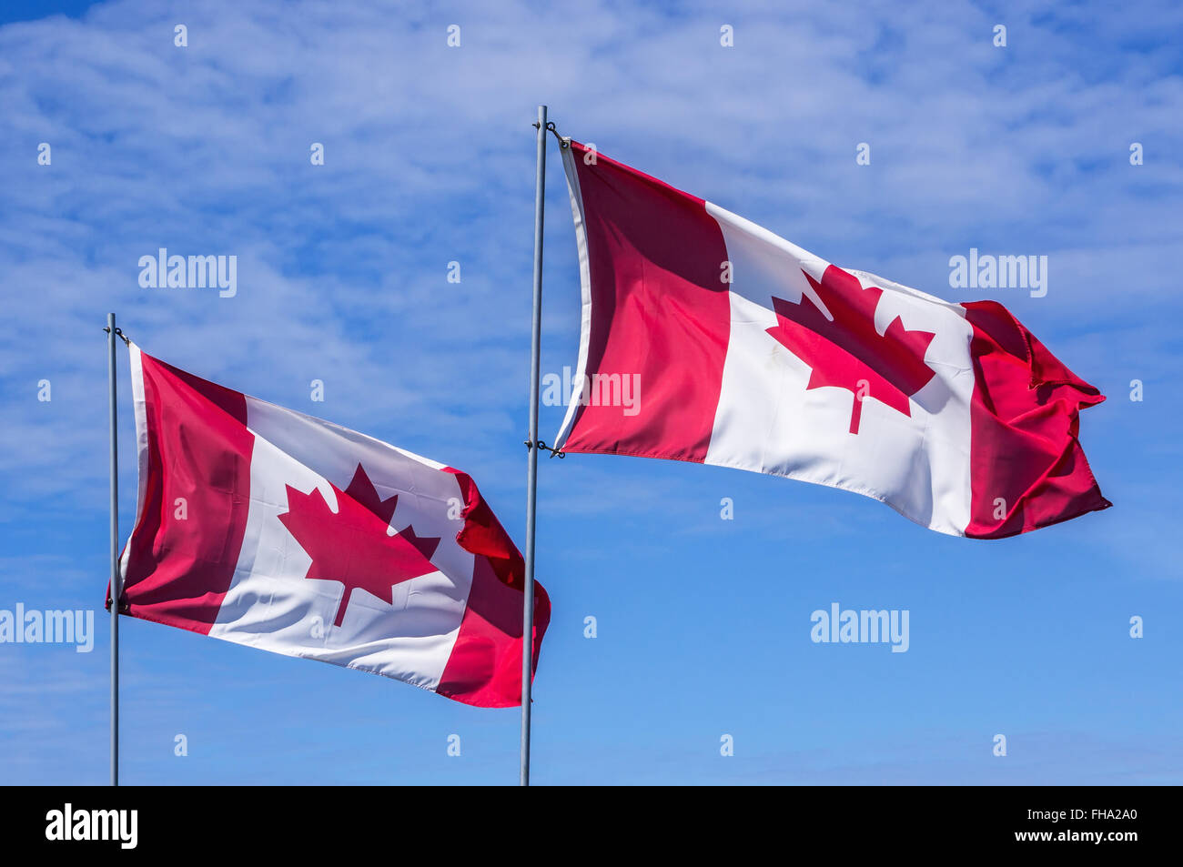 Two Canadian flags in front of blue sky Stock Photo - Alamy