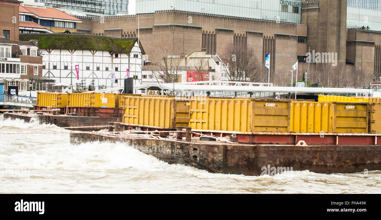 Tug pulling two barges containing yellow containers on River Thames ...