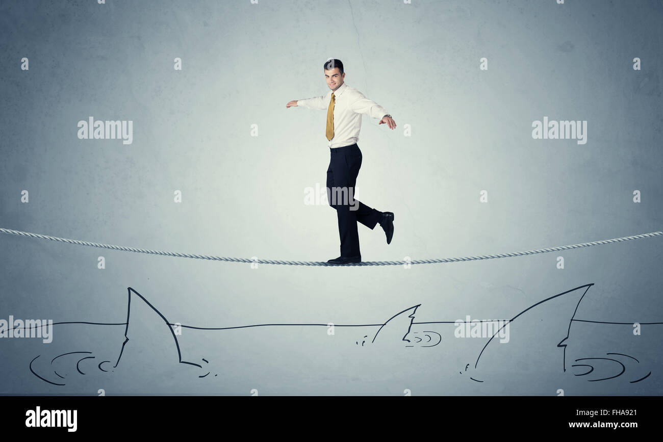 Businessman walking on rope above sharks Stock Photo - Alamy