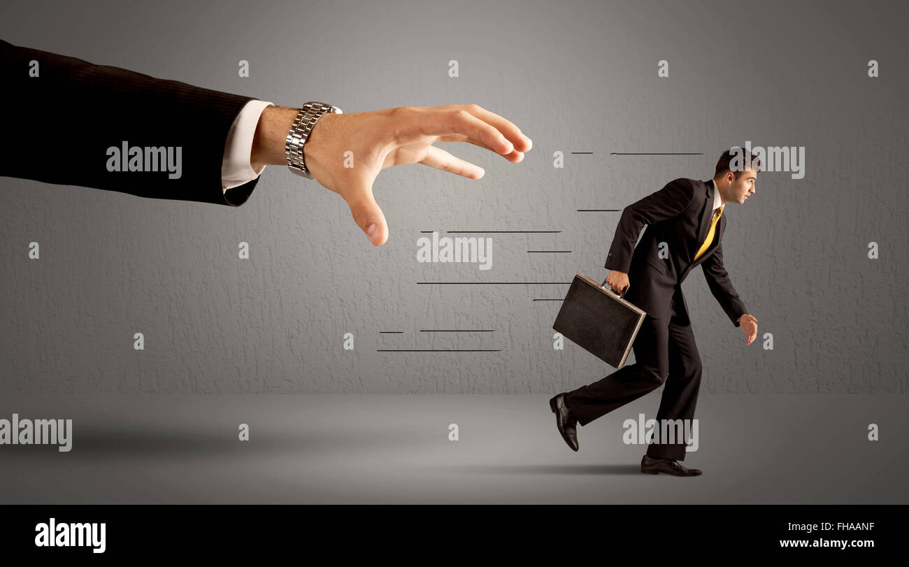 Businessman running away from a huge hand Stock Photo - Alamy