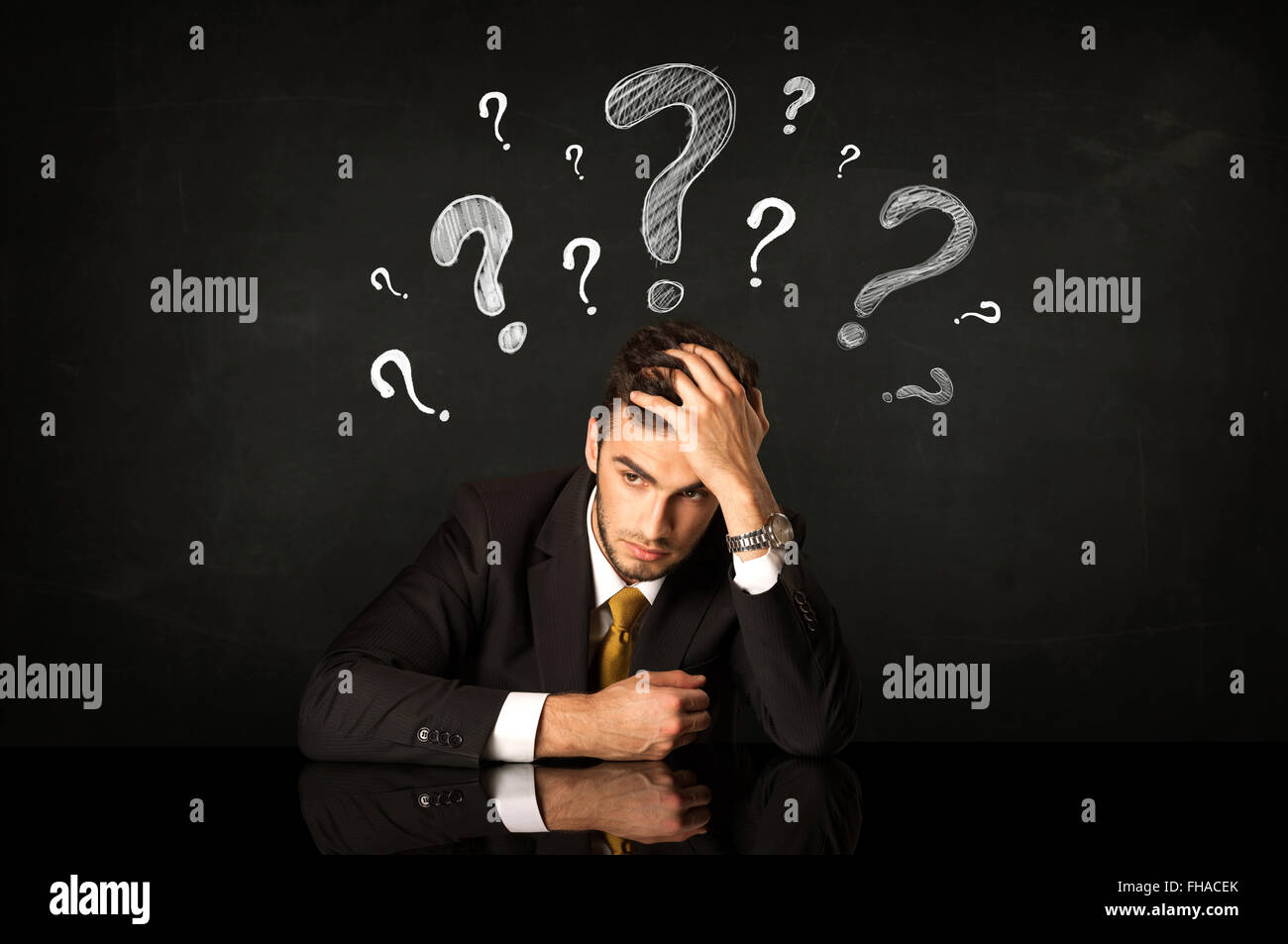 Sitting businessman under question marks Stock Photo - Alamy