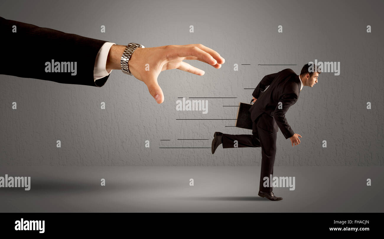 Businessman running away from a huge hand Stock Photo - Alamy