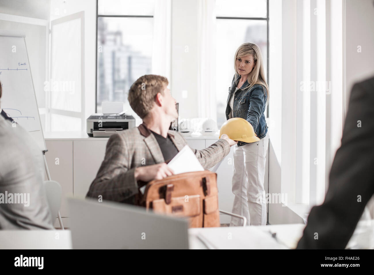 Woman handing over hard hat to colleague in office Stock Photo - Alamy