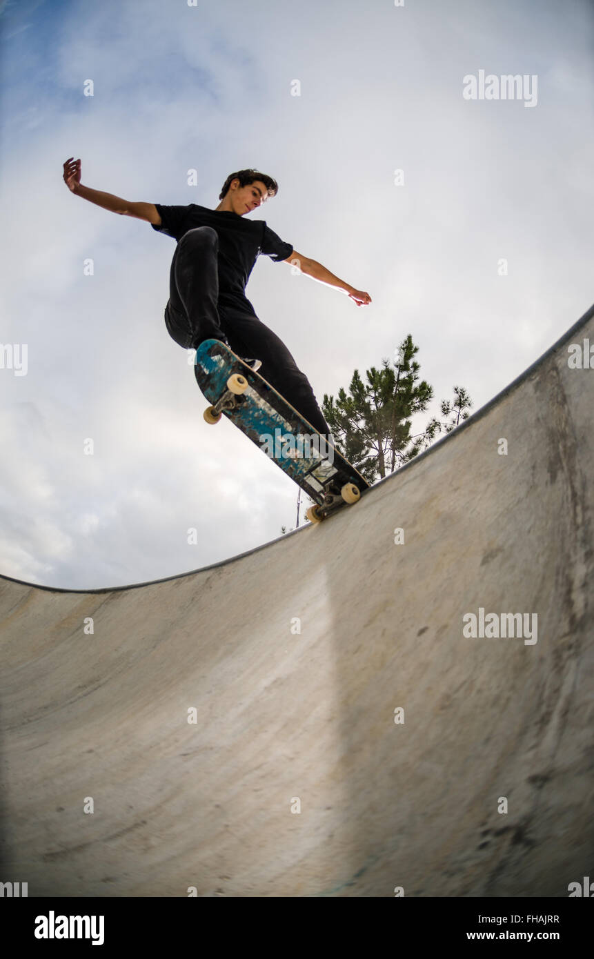 Skateboarder doing a tail slide on a croncrete pool at the skate park ...