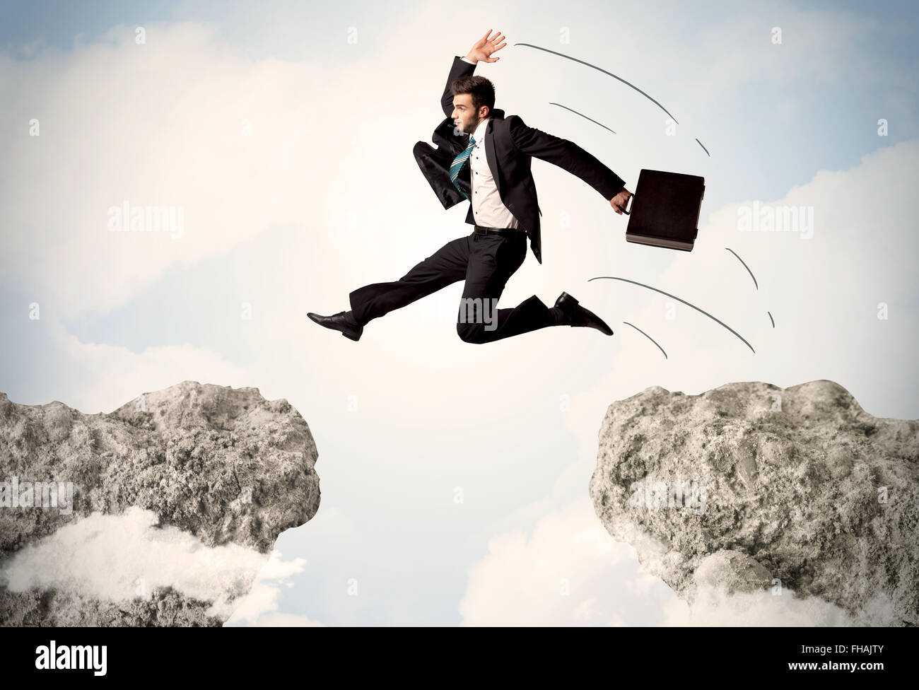 Happy business man jumping over a cliff Stock Photo - Alamy