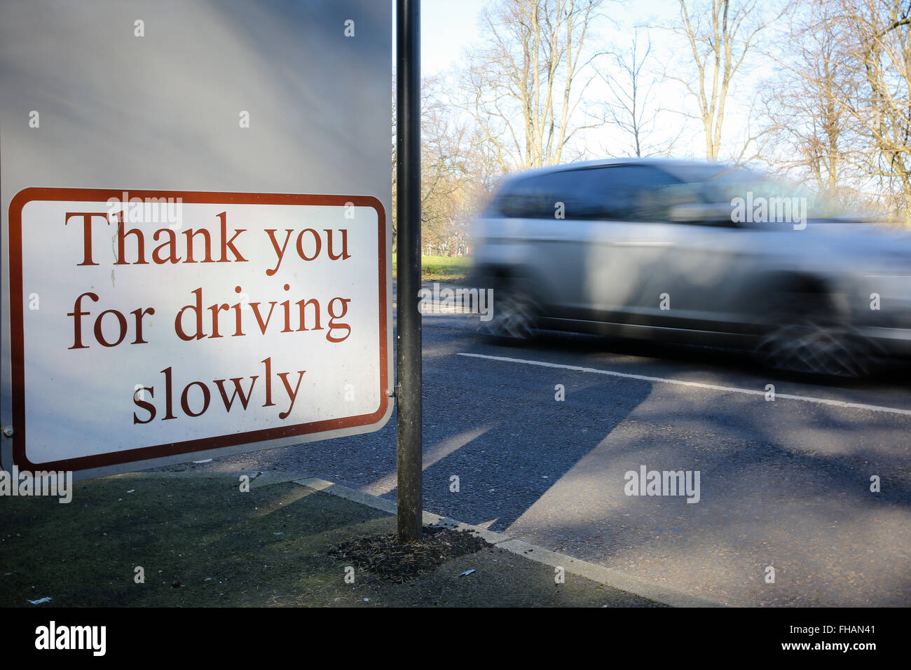 A road safety sign - Thank you for driving slowly - with a speeding car ...