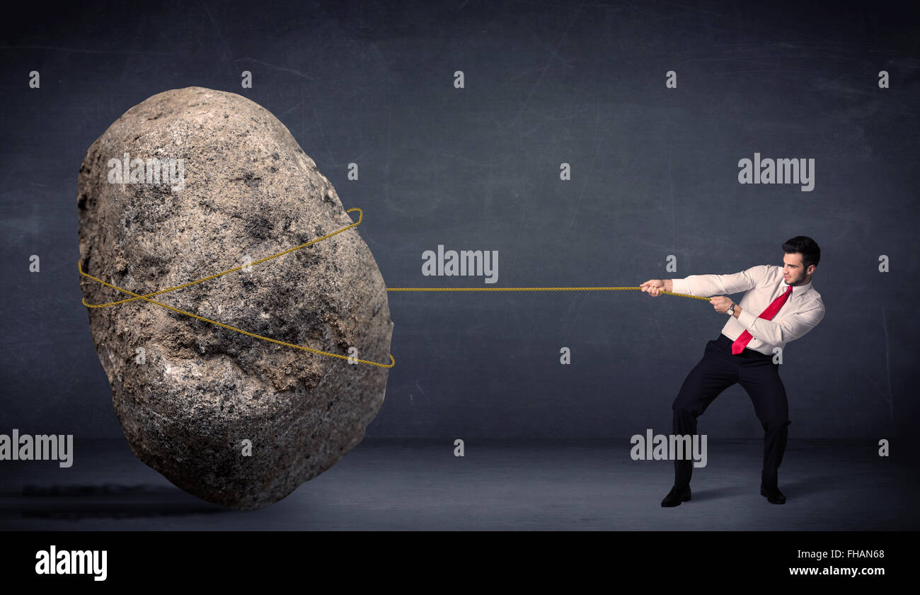 Businessman pulling huge rock with a rope Stock Photo - Alamy