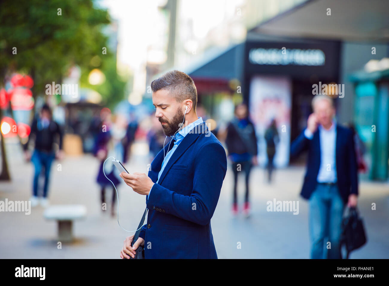 Manager with smartphone listening music outside in the street Stock ...