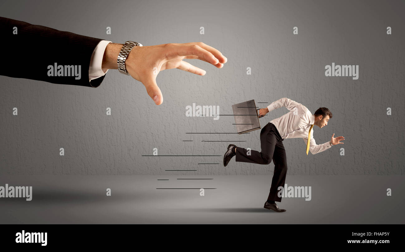 Businessman running away from a huge hand Stock Photo - Alamy