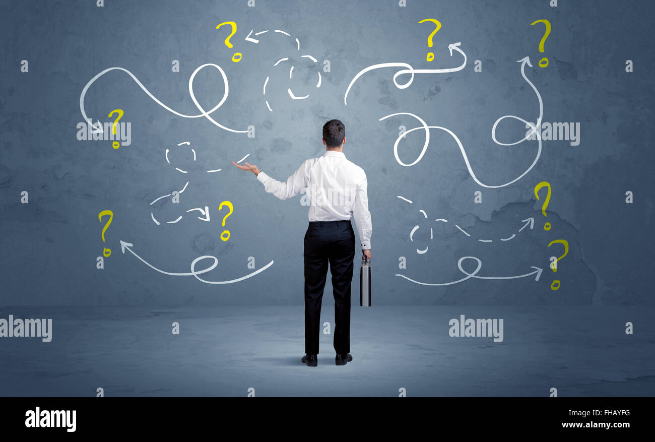 Unsure businessman with question marks Stock Photo - Alamy