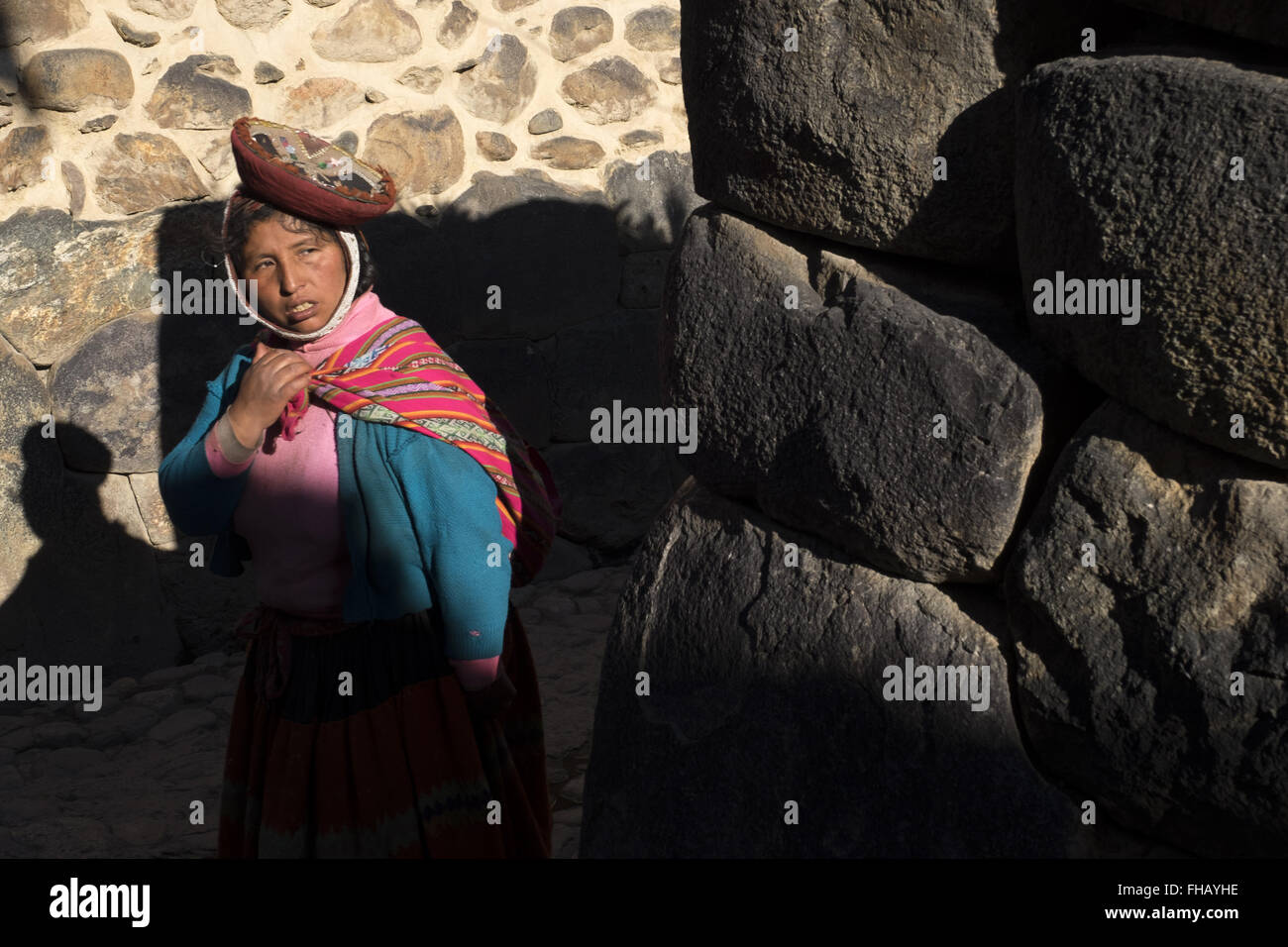 A woman dressed in traditional clothes walks among the Inca walls of ...