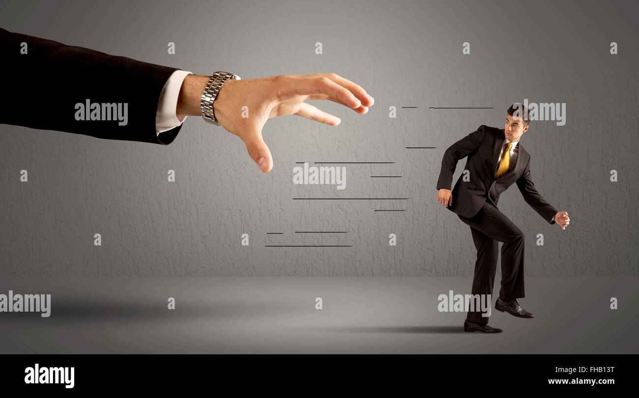 Businessman running away from a huge hand Stock Photo - Alamy