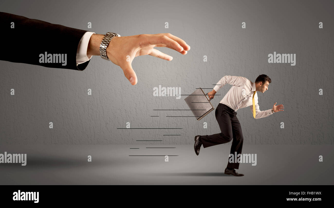 Businessman running away from a huge hand Stock Photo - Alamy
