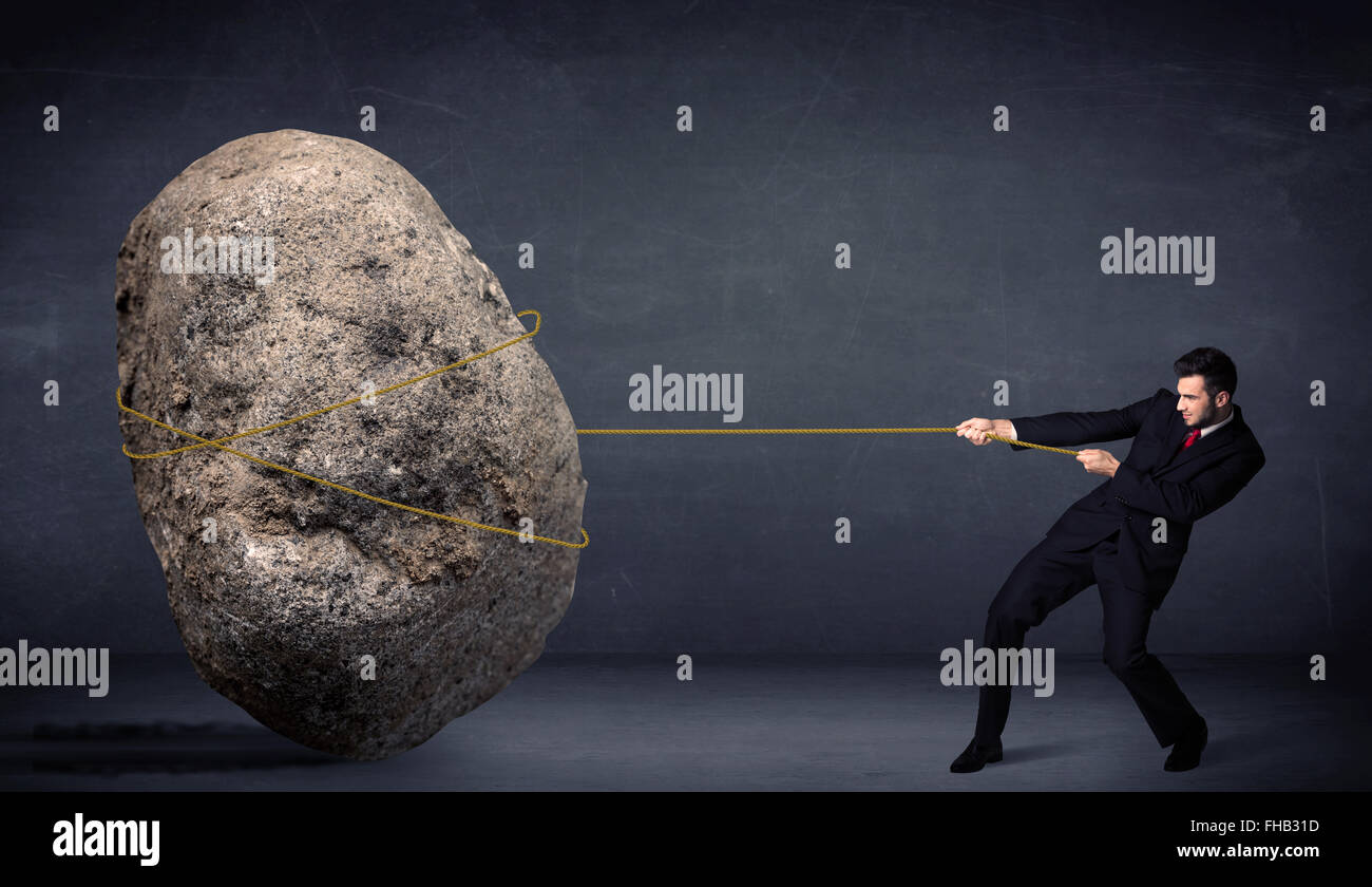 Businessman pulling huge rock with a rope Stock Photo - Alamy