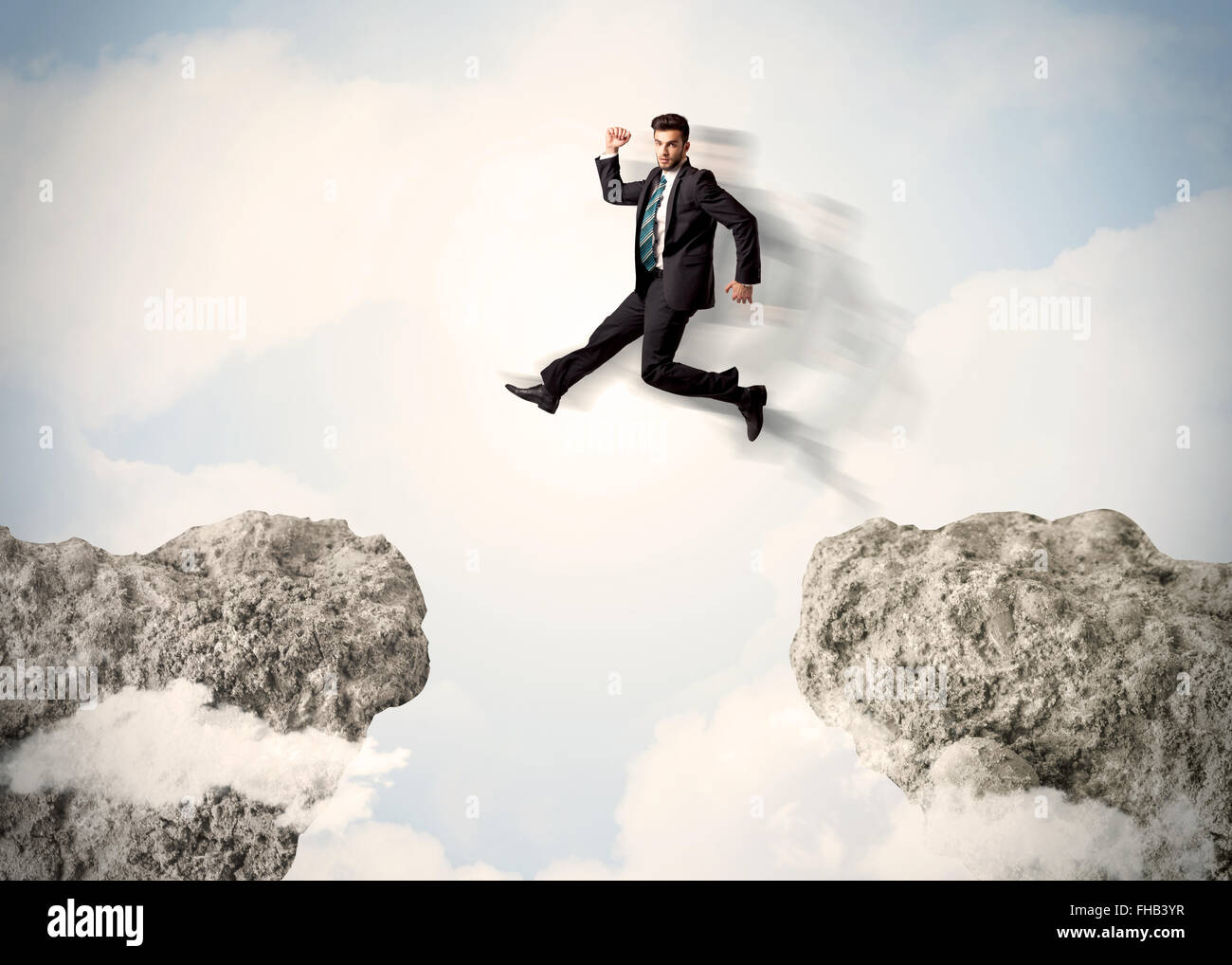 Happy business man jumping over a cliff Stock Photo - Alamy
