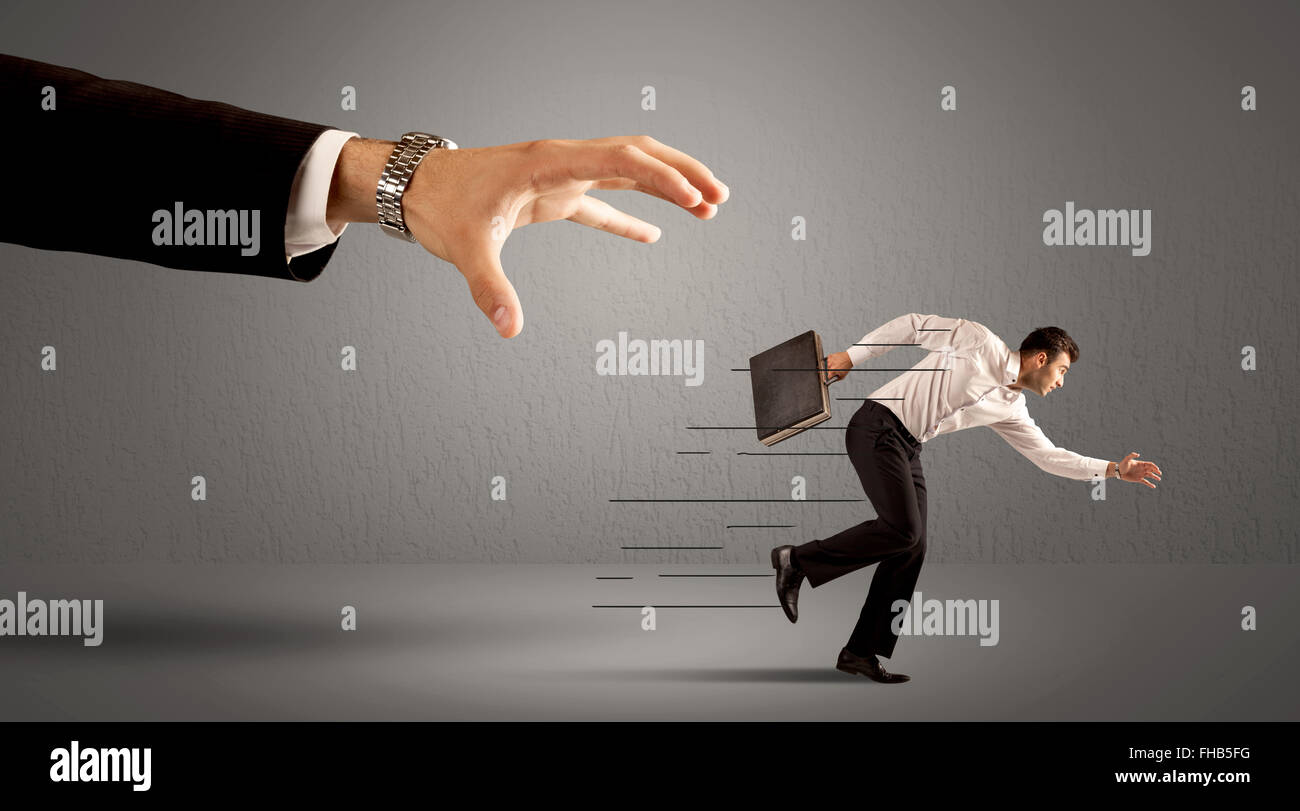 Businessman running away from a huge hand Stock Photo - Alamy