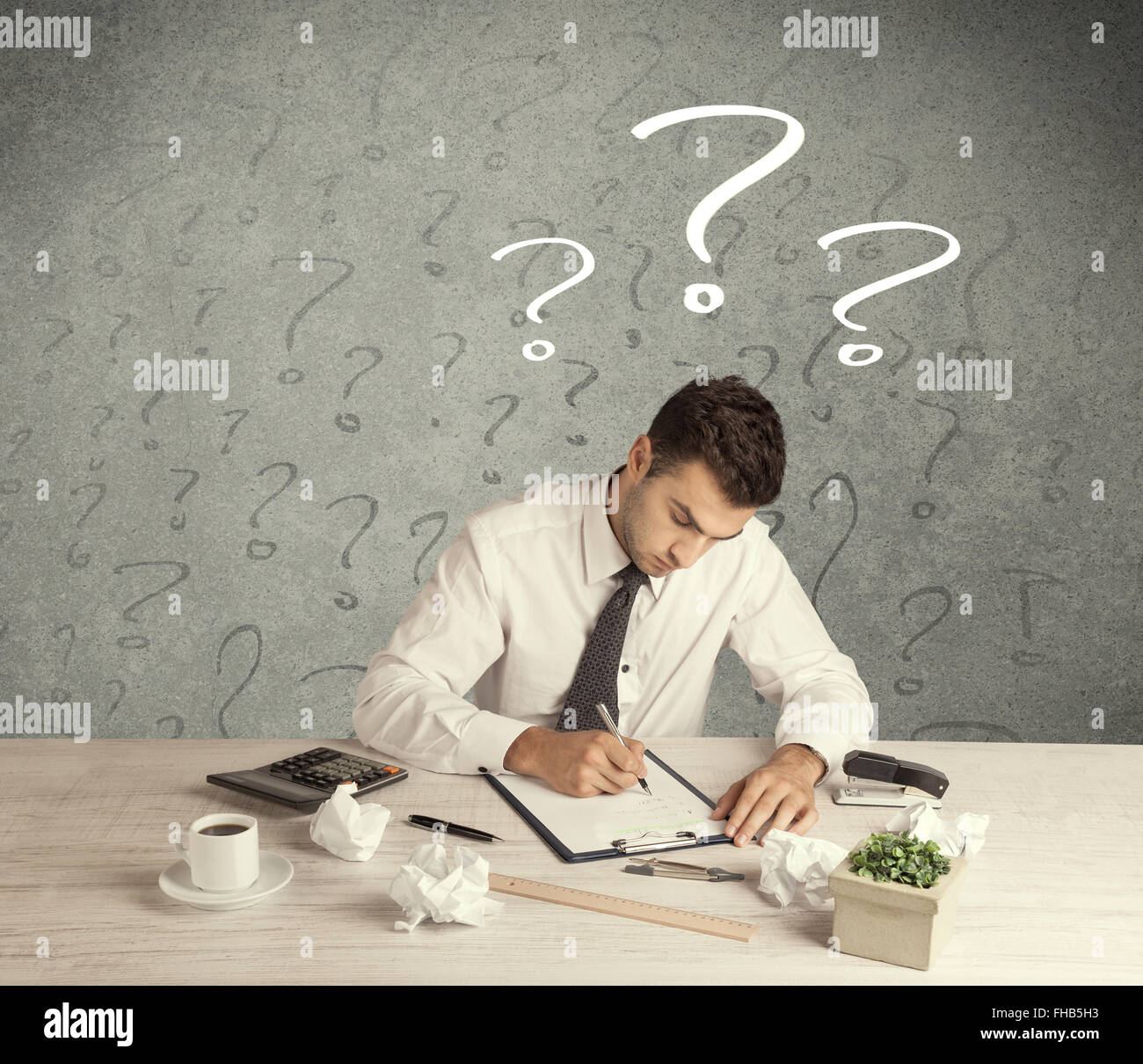 Businessman at desk with question mark Stock Photo - Alamy
