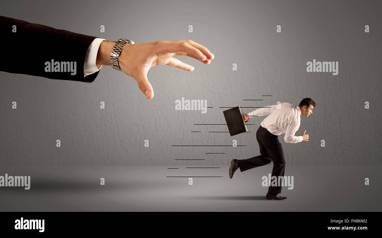 Businessman running away from a huge hand Stock Photo - Alamy
