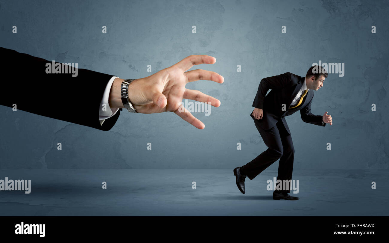 Business man running away from a huge hand concept Stock Photo - Alamy