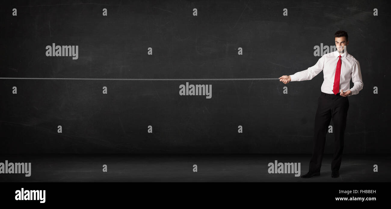 Businessman pulling rope on grey background Stock Photo - Alamy