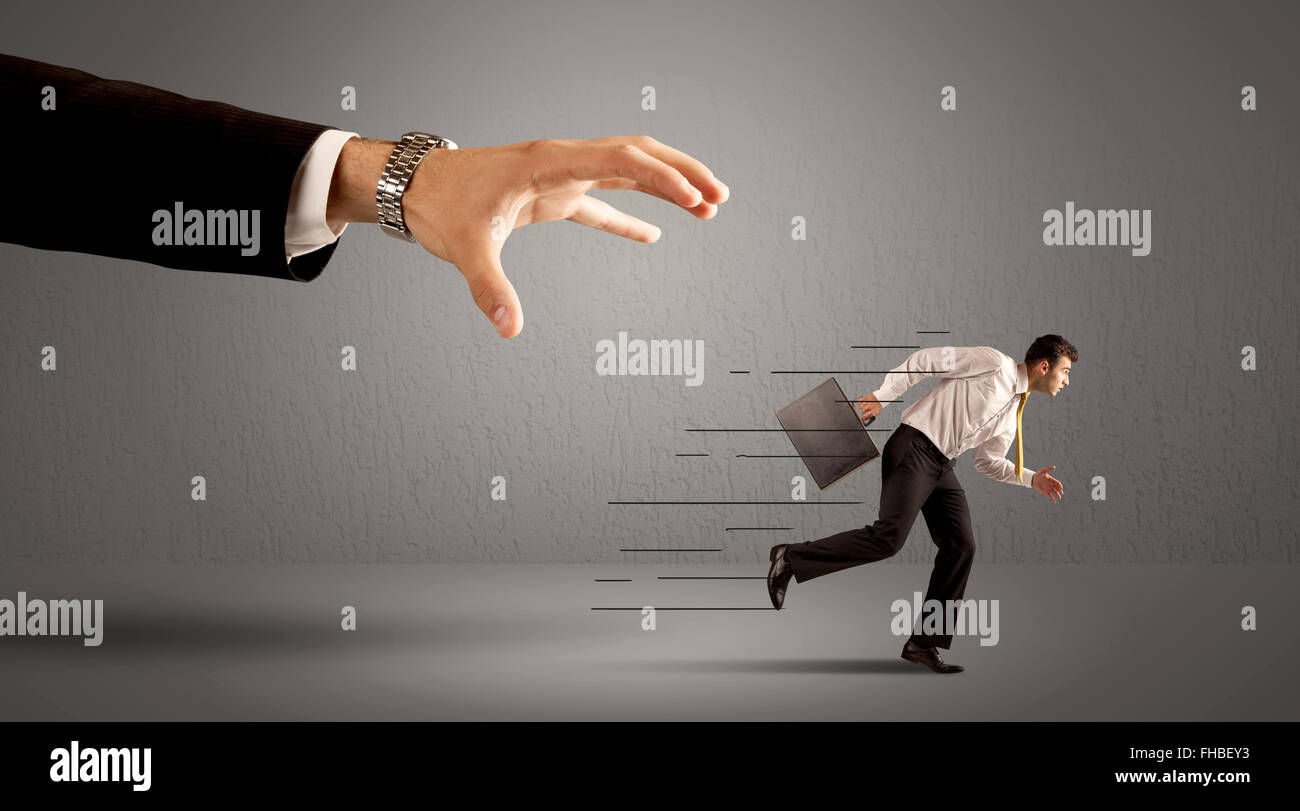 Businessman running away from a huge hand Stock Photo - Alamy