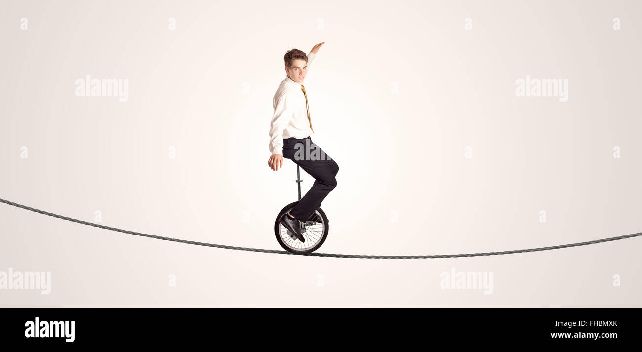 Extreme business man riding unicycle on a rope Stock Photo - Alamy
