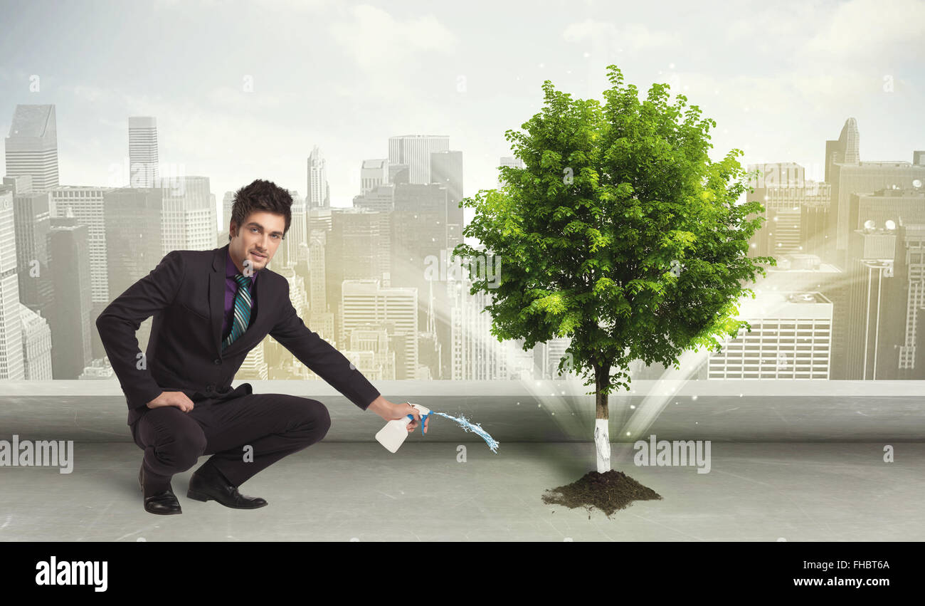Businessman watering green tree on city background Stock Photo - Alamy