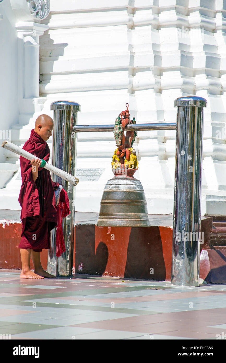 YANGON, MYANMAR - NOVEMBER 25, 2015 - Buddhist monk ringing the bell in ...