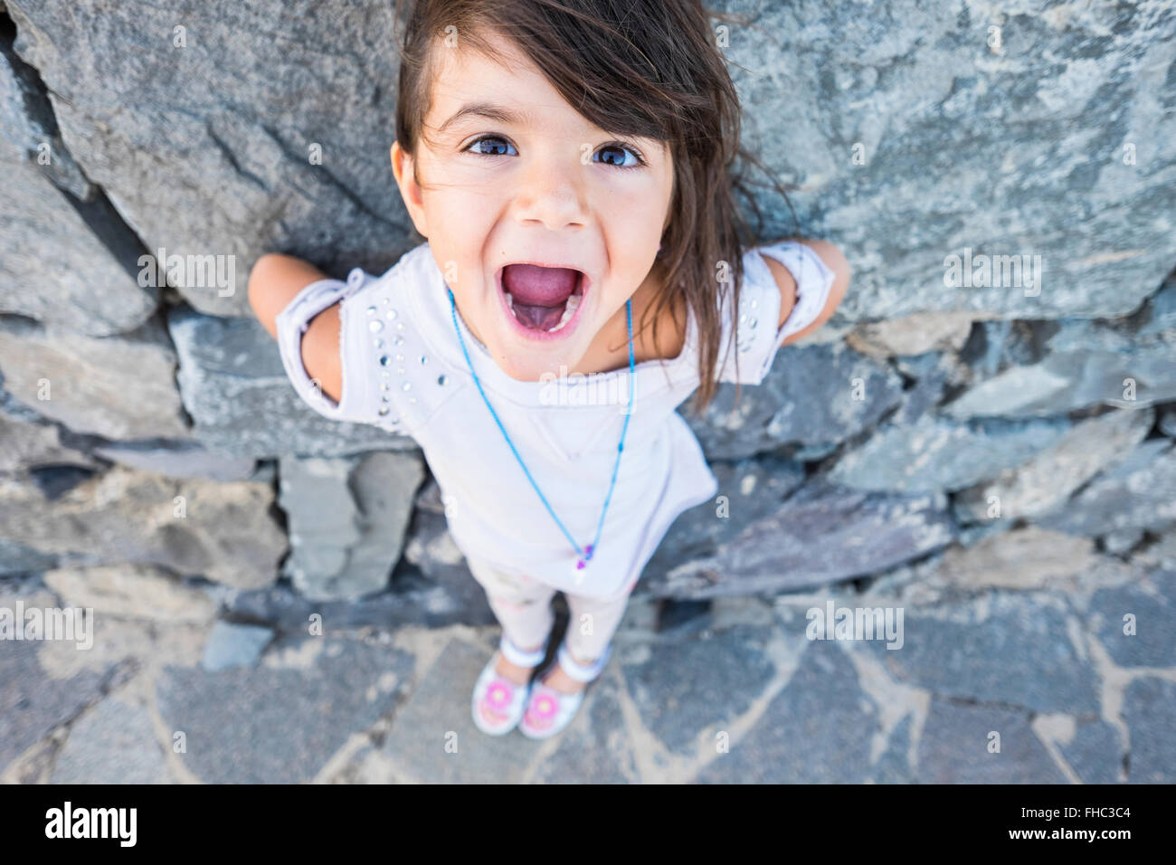Portrait of little girl with mouth open in front of a rock face Stock ...