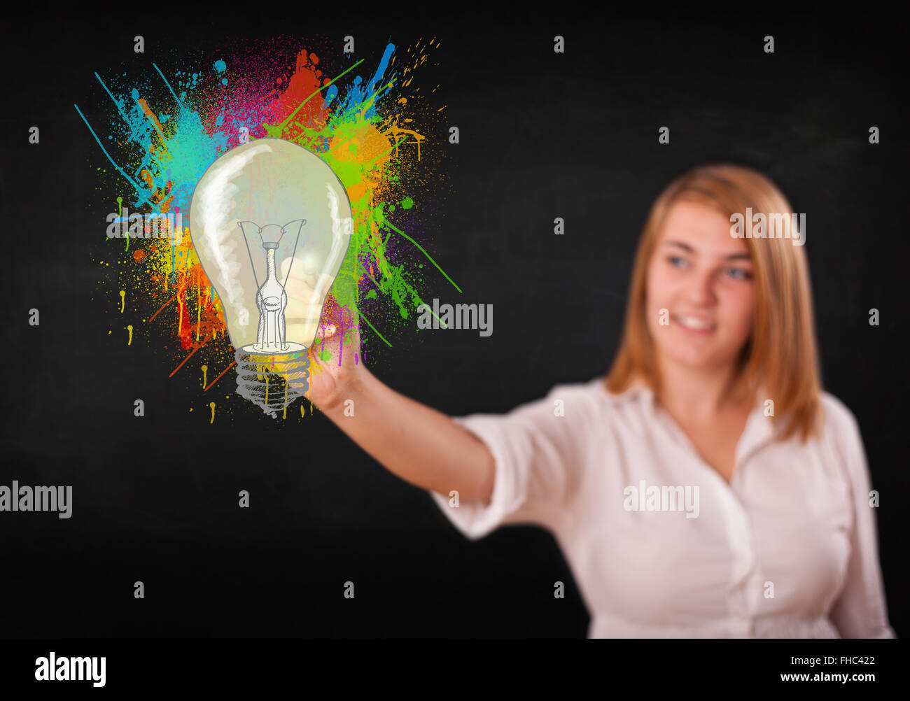 Young lady drawing a colorful light bulb with colorful splashes Stock ...