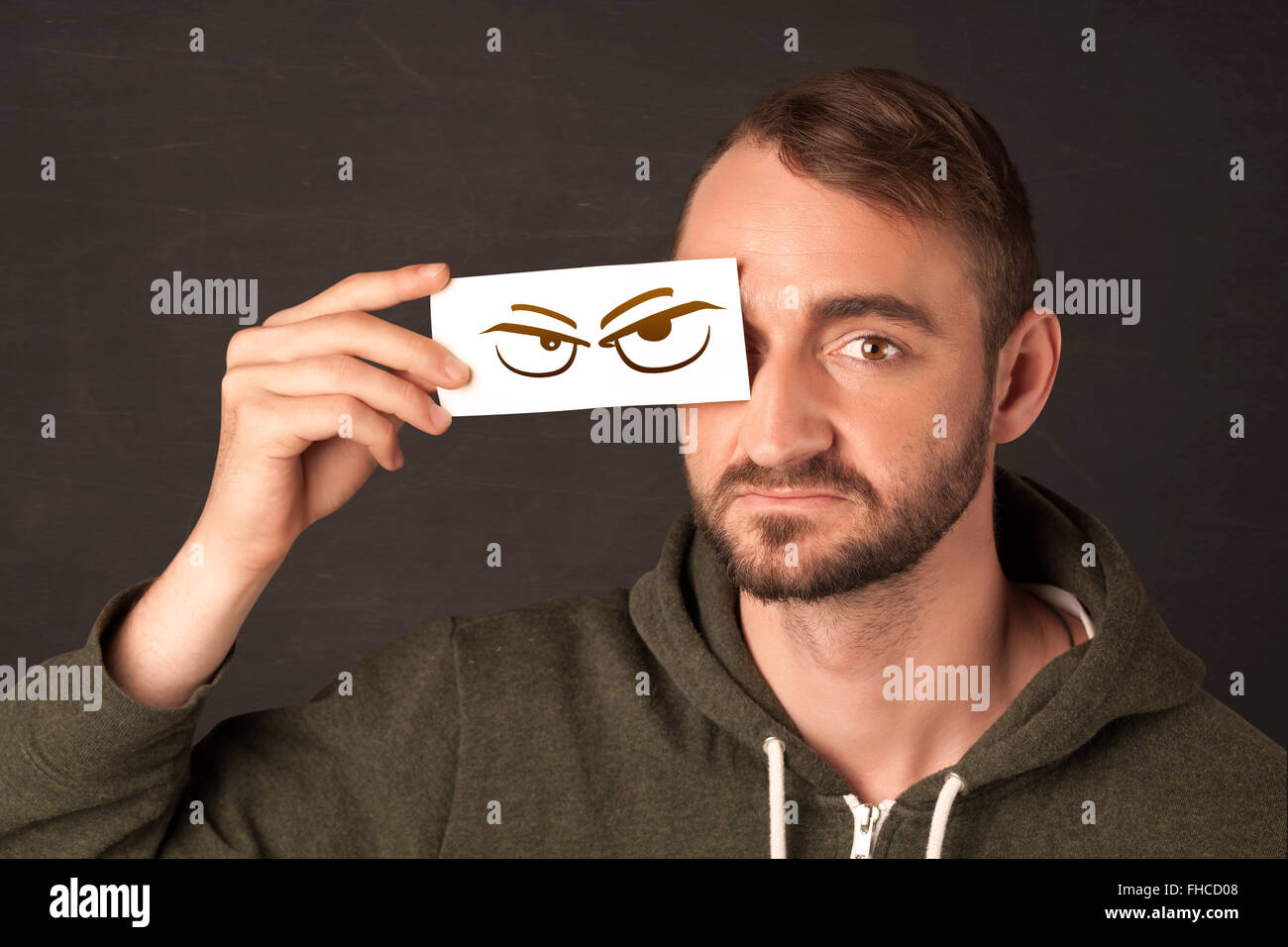 Young person holding paper with angry eye drawing Stock Photo - Alamy