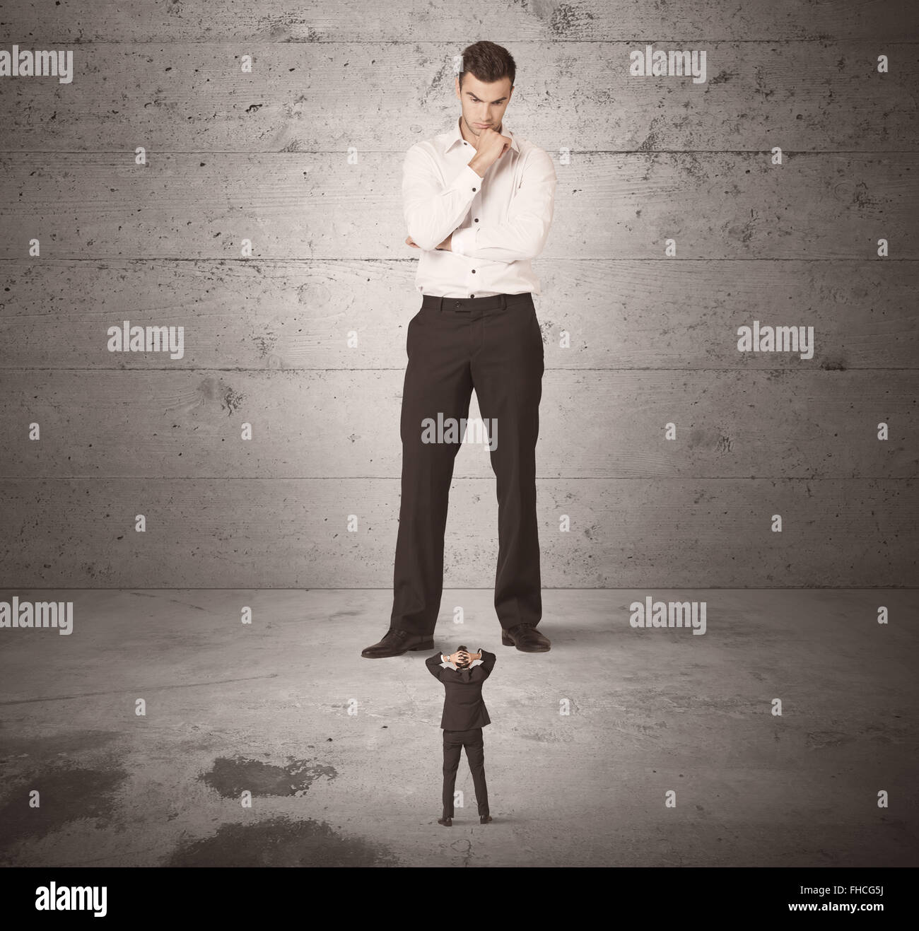 Huge business guy looking at small coworker Stock Photo - Alamy