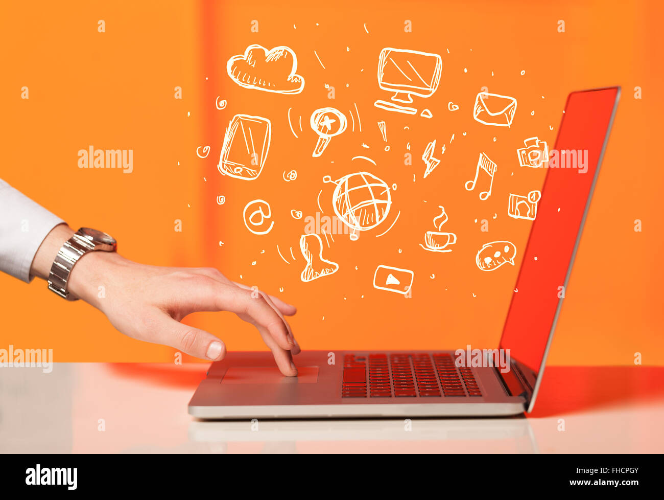 Hand writing on notebook computer with media icons Stock Photo - Alamy