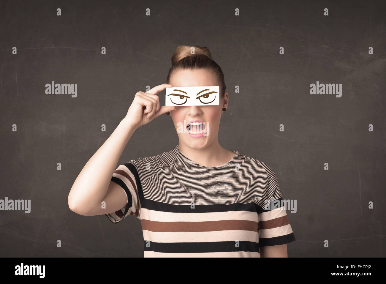 Young person holding paper with angry eye drawing Stock Photo - Alamy