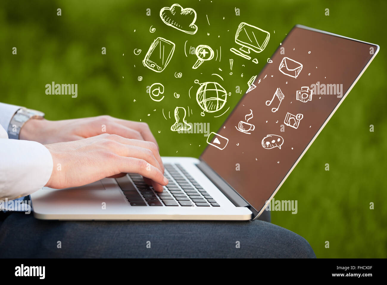 Hand writing on notebook computer with media icons Stock Photo - Alamy