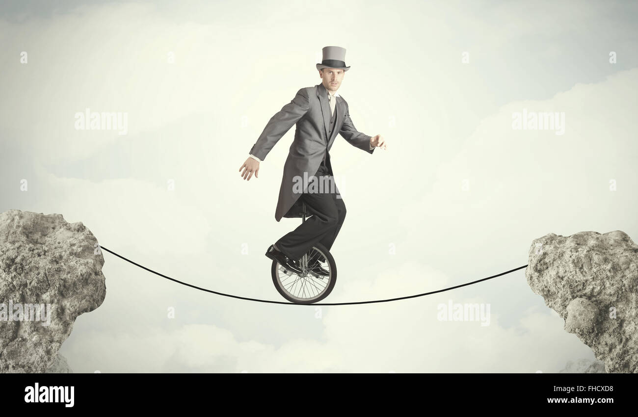 Brave business man riding an mono cycle between cliffs Stock Photo - Alamy
