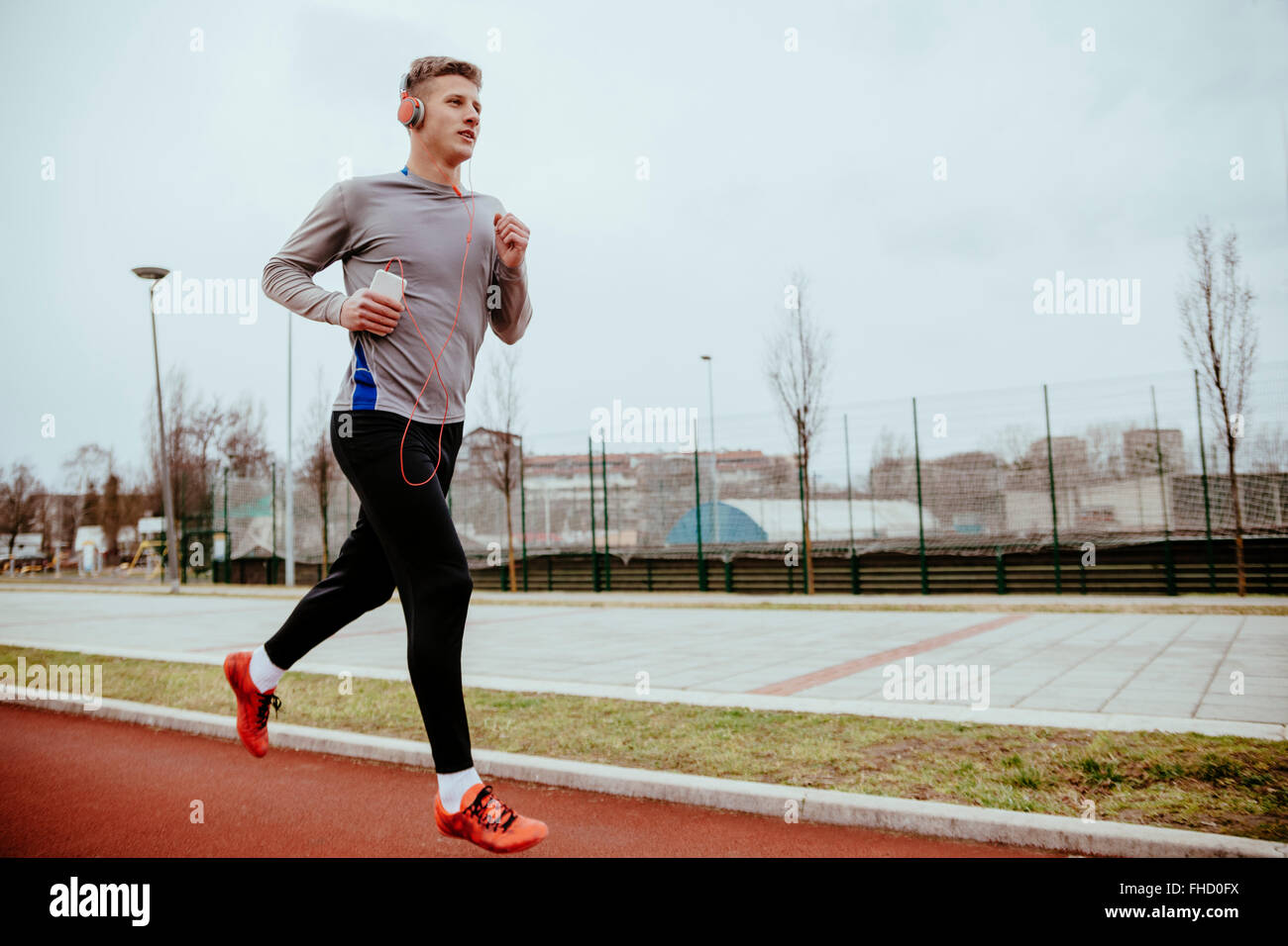 Young man running on tartan track Stock Photo - Alamy