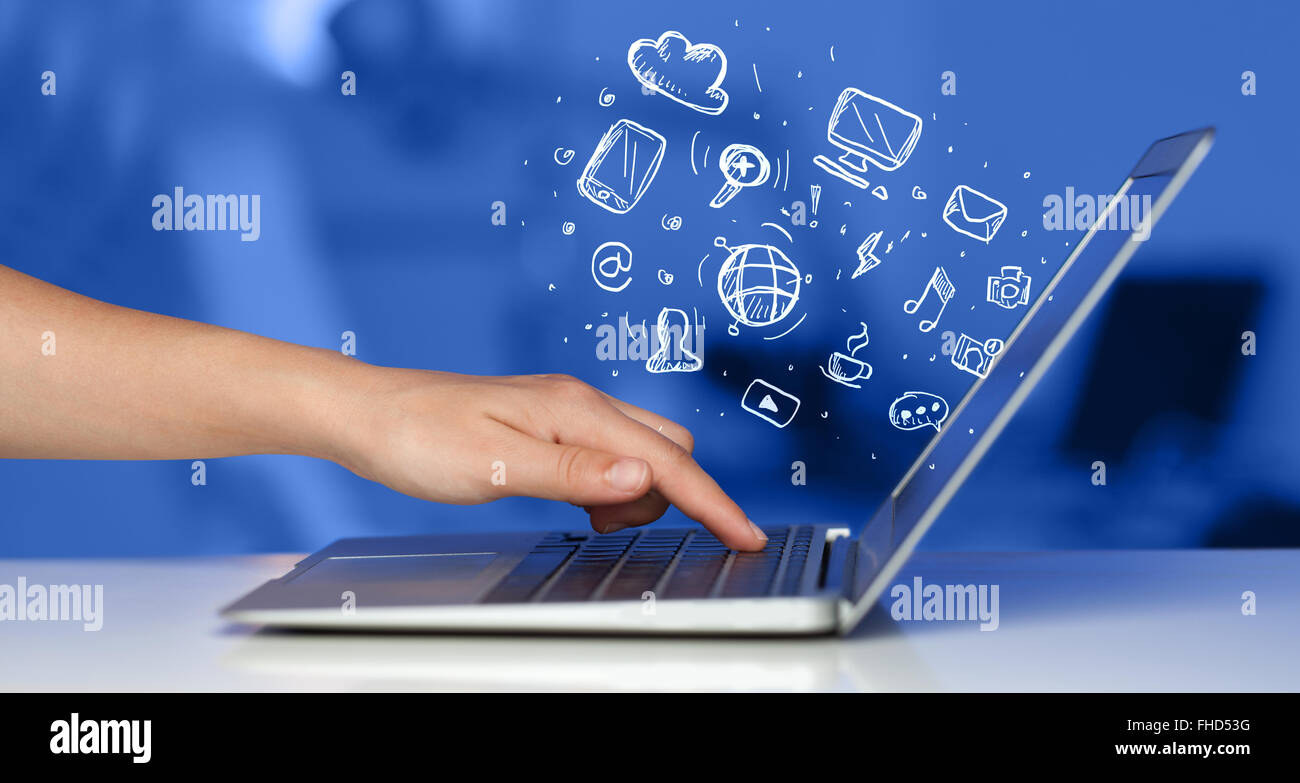 Hand writing on notebook computer with media icons Stock Photo - Alamy