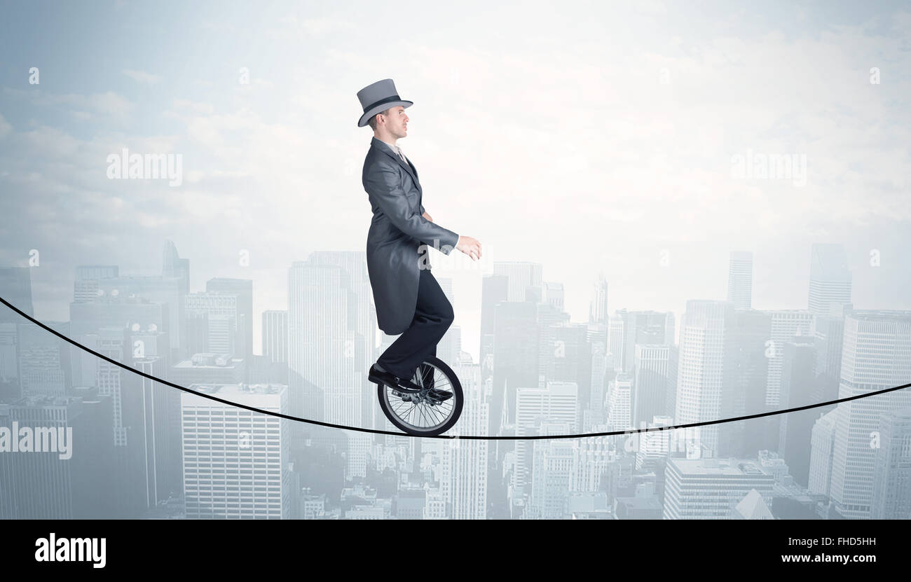 Brave guy riding a monocycle on a rope above cityscape Stock Photo - Alamy