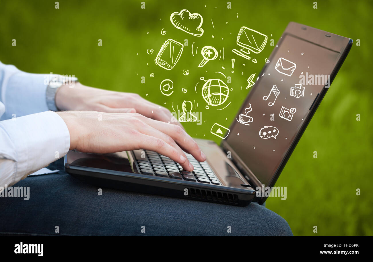 Hand writing on notebook computer with media icons Stock Photo - Alamy