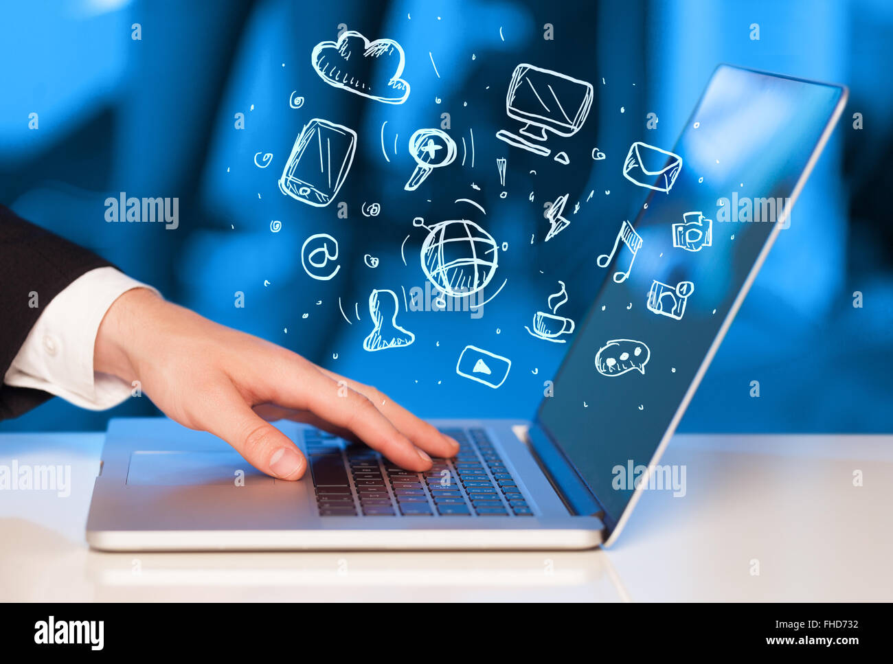 Hand writing on notebook computer with media icons Stock Photo - Alamy