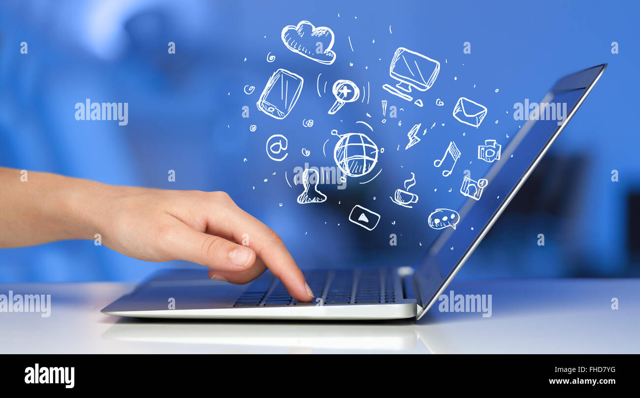 Hand writing on notebook computer with media icons Stock Photo - Alamy