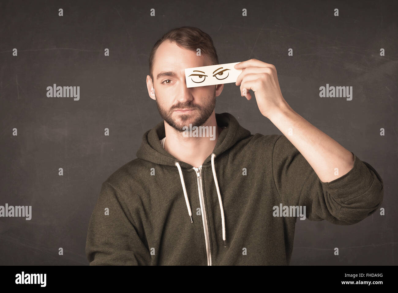 Young person holding paper with angry eye drawing Stock Photo - Alamy