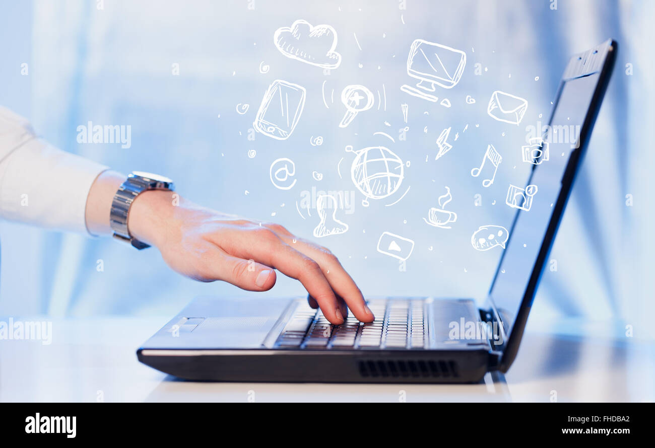 Hand writing on notebook computer with media icons Stock Photo - Alamy