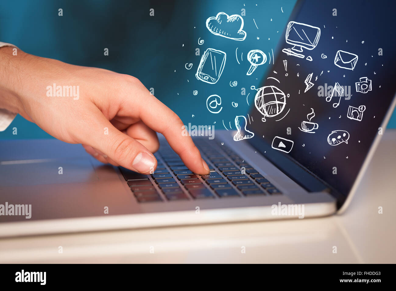 Hand writing on notebook computer with media icons Stock Photo - Alamy