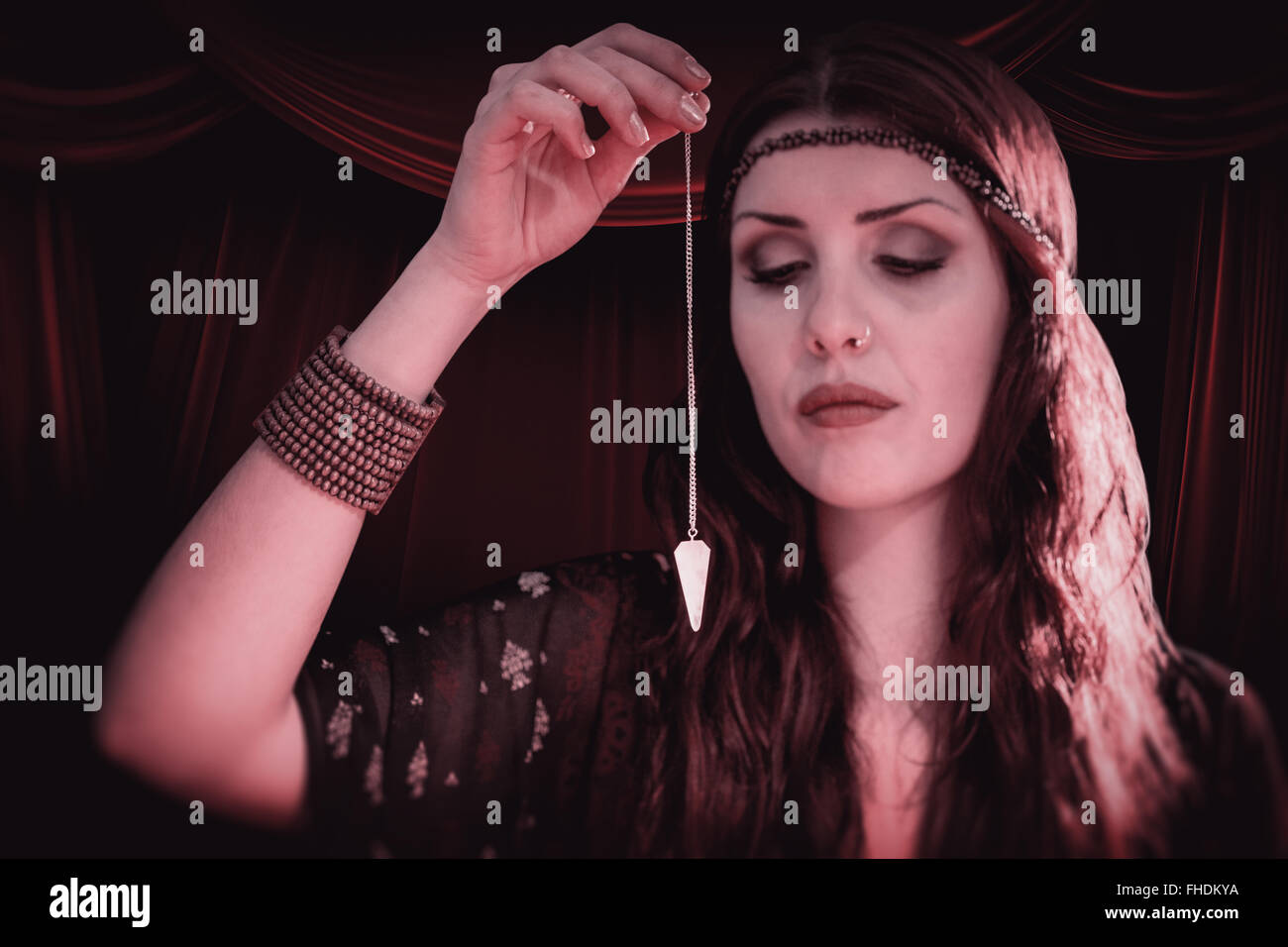 Composite image of fortune teller holding pendulum with eyes closed ...