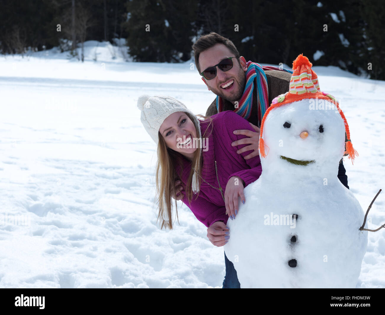 portrait of happy young couple with snowman Stock Photo - Alamy